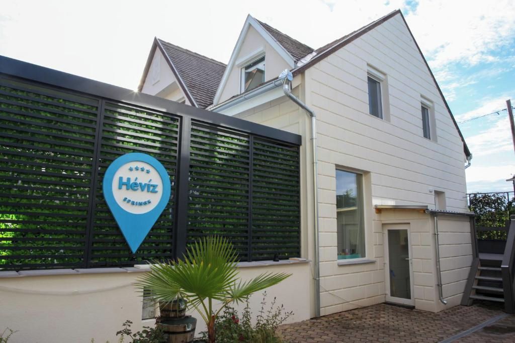 Uma casa moderna de dois andares com uma placa indicando um hotel chamado 'Héviz Springs'.