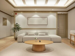 Uma sala de estar moderna com uma mesa de centro redonda de madeira, um sofá bege e uma planta em vaso.