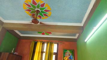 Quarto com ventoinha no teto, janela com cortinas e parede com um design colorido.