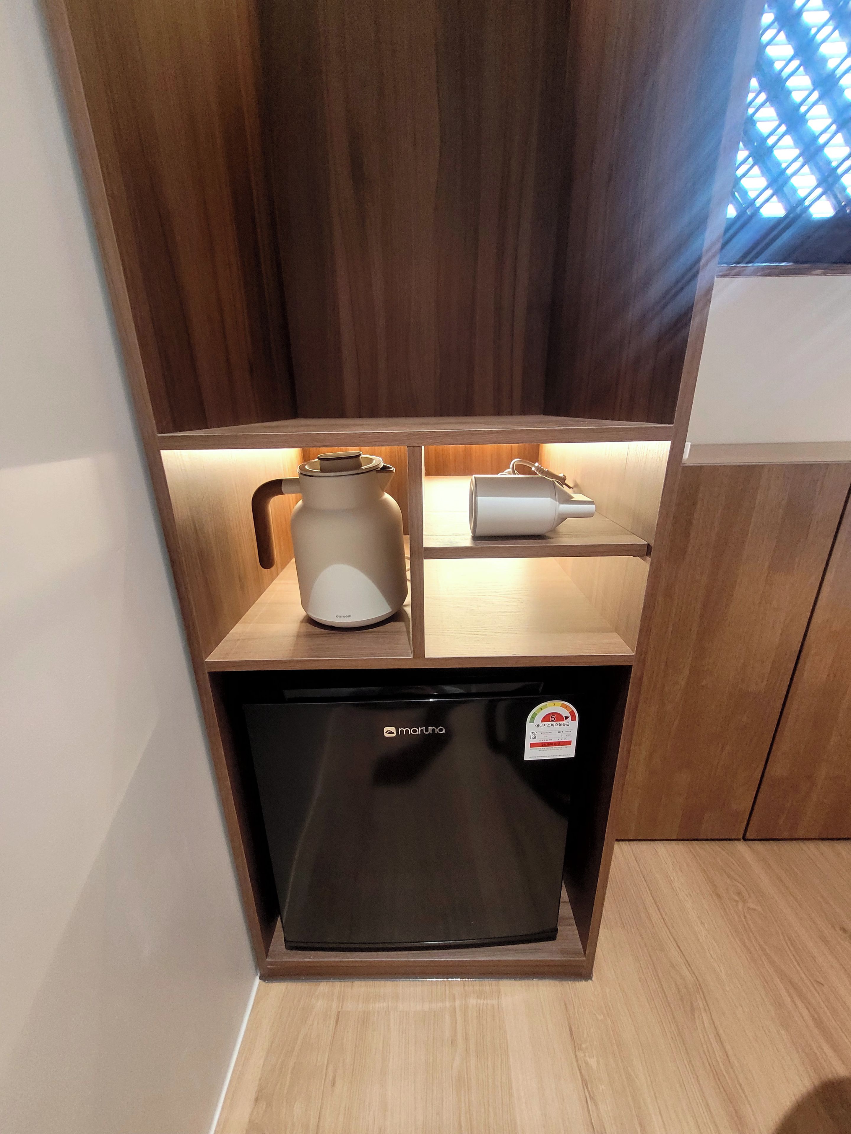 Cozinha compacta com lava-louças embutida, chaleira e uma pequena estante com uma bolsa de mão.
