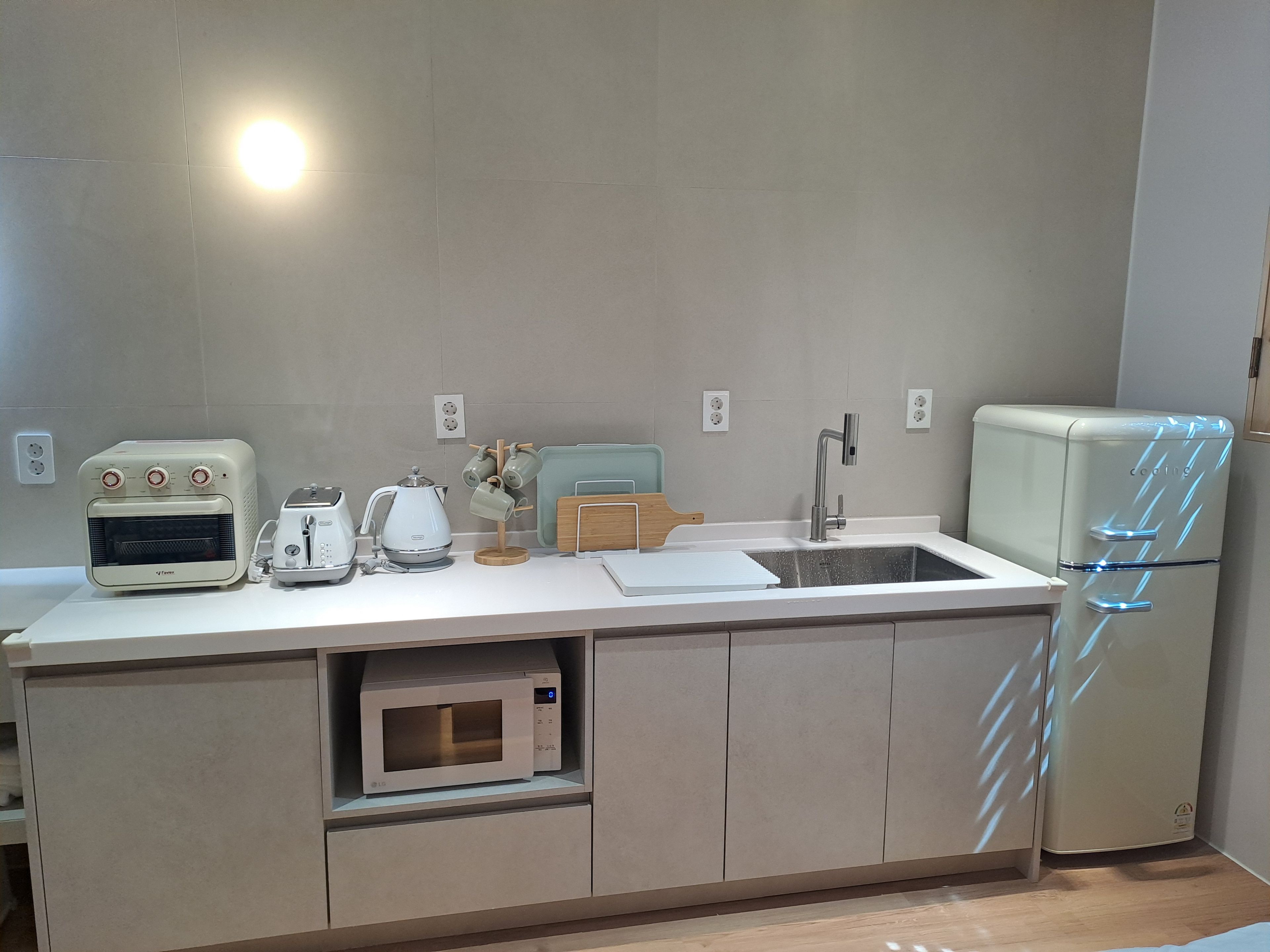 Cozinha moderna equipada com micro-ondas, torradeira, chaleira e frigorífico.