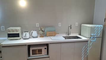 Cozinha moderna equipada com micro-ondas, torradeira, chaleira e frigorífico.