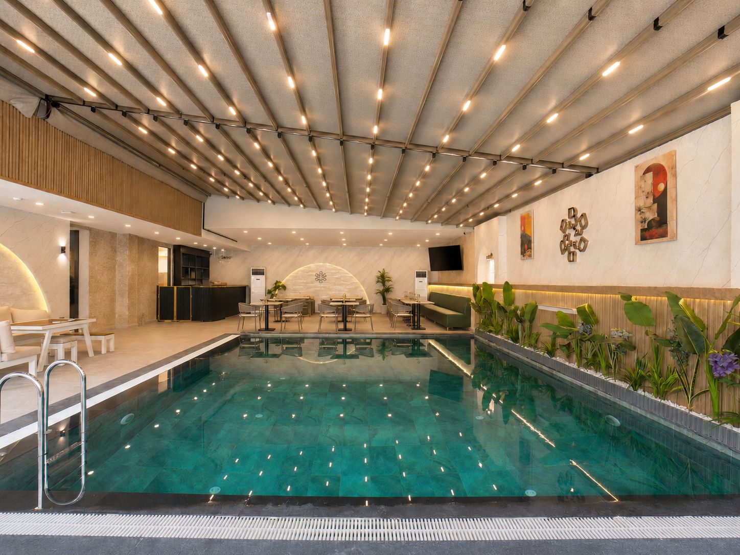 Piscina interior com teto de vigas paralelas e iluminação embutida, rodeada por áreas de estar e um balcão de recepção.