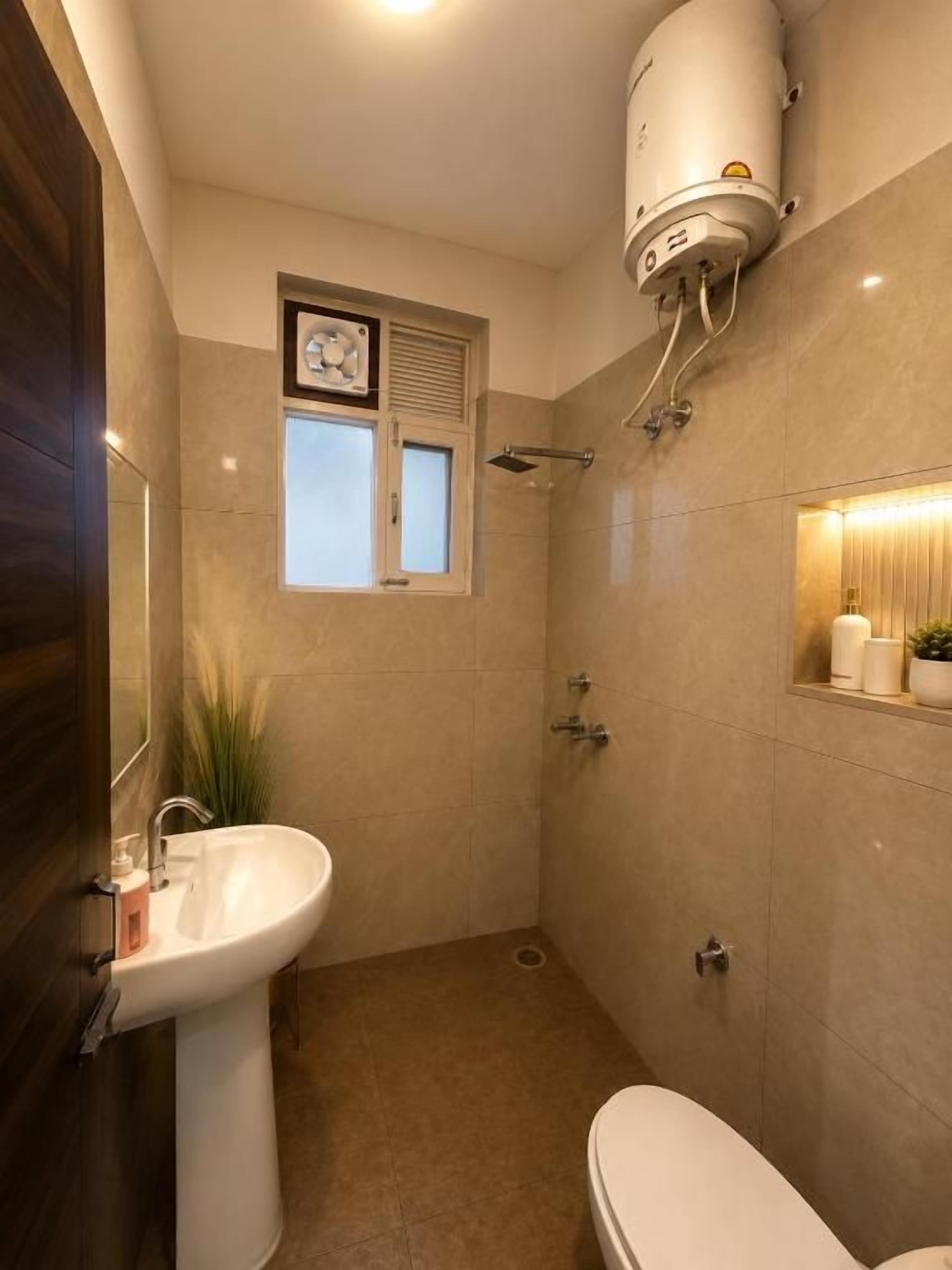 Casa de banho compacta com lavatório suspenso, sanita, chuveiro e aquecedor embutido.
