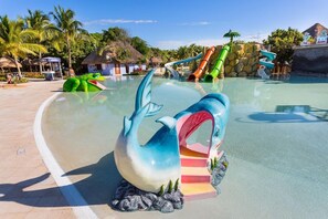 Parque aquático com uma grande escultura de golfinho, escorregadores e piscina.