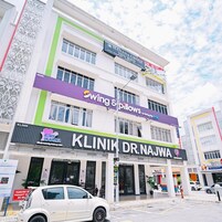 Um edifício com vários andares com a sinalização 'Swing Spilows' e 'Klinik Dr. Najwa'.