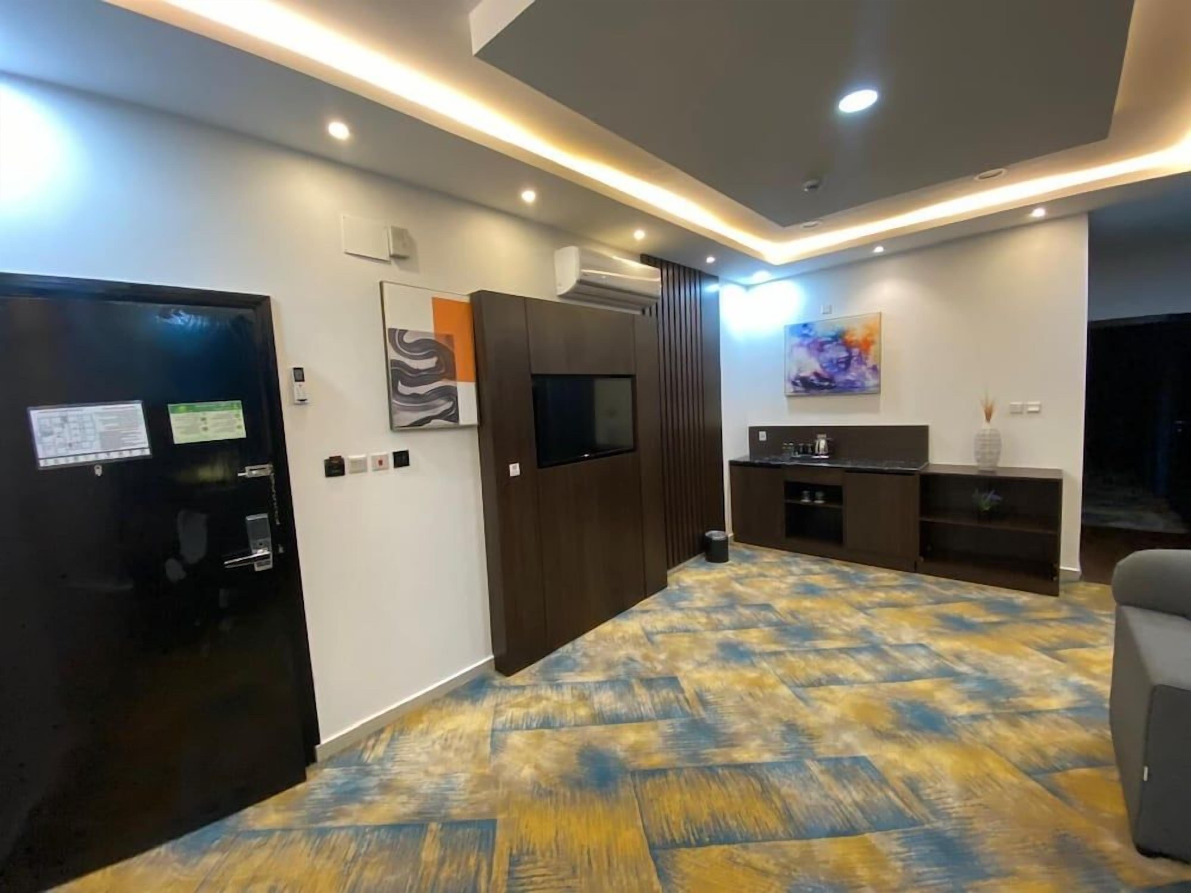 Quarto moderno com carpete estampado, painel de entretenimento embutido e porta com painel de controle.