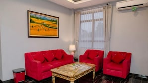 Quarto com sofá vermelho, mesa de centro de mármore, luminária e pintura na parede.