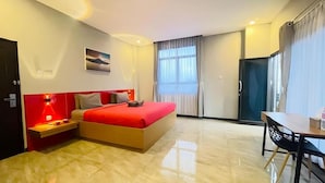 Quarto de hotel com cama, mesa de cabeceira, luminária e vista para o exterior.