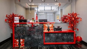 Balcão de recepção de hotel com esquema de cores vermelho e preto, um relógio e um espelho acima.