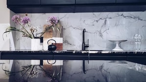 Cozinha moderna com bancada de mármore, torneira preta, um vaso branco com flores e tábua de corte de madeira.