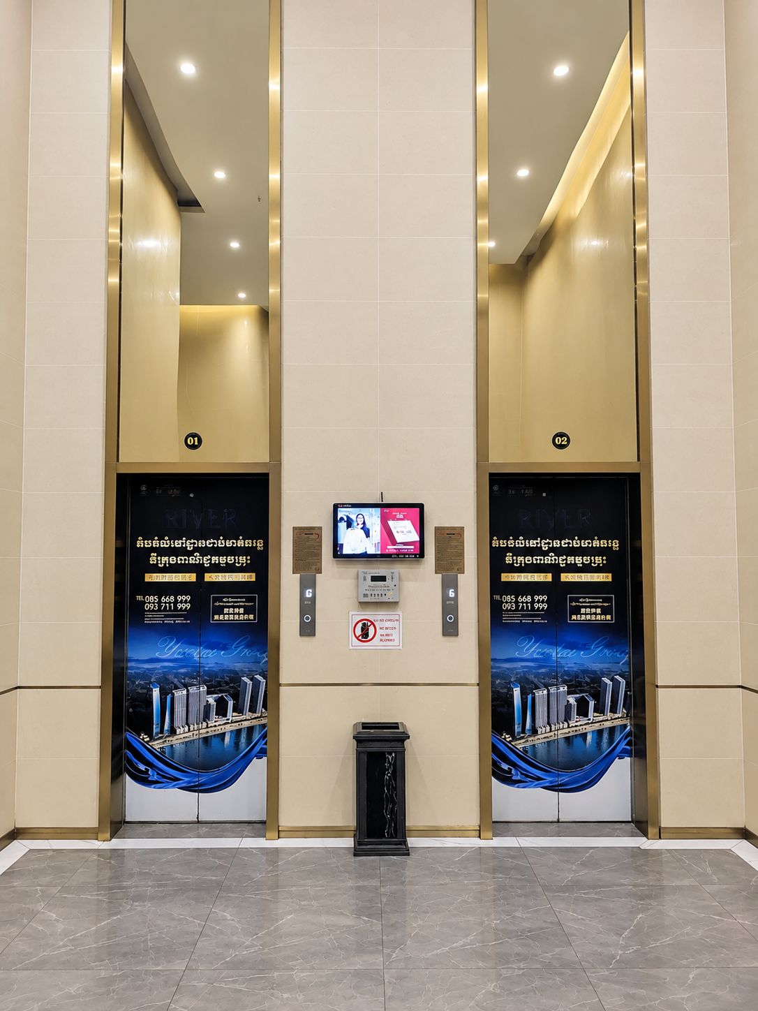 Interior de elevador moderno com painéis digitais, instruções de emergência e um anúncio de paisagem urbana.