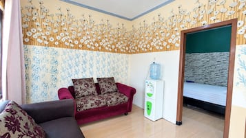 Quarto com sofá, dispensador de água e cama com parede de pedra.
