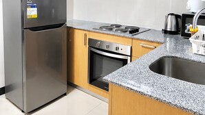 Cozinha moderna com eletrodomésticos de aço inoxidável, armários de madeira e bancada de granito.
