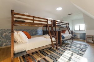 Quarto com beliches, carpete estampado, móveis de madeira e uma janela.