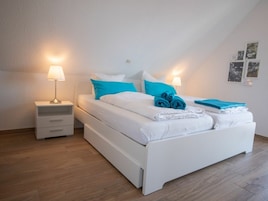 Quarto com uma cama de solteiro, duas mesas de cabeceira e um criado-mudo.