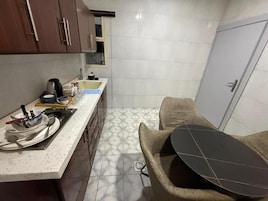 Cozinha compacta com bancada, pia e um pequeno espaço de refeições com mesa e cadeira.