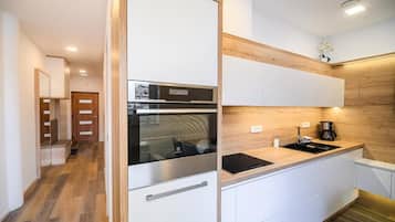 Cozinha moderna com armários brancos, forno embutido e bancada de madeira.