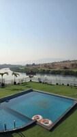 Piscina com vista para um rio e colinas ao longe.