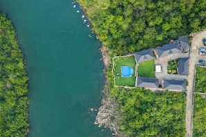 Vista aérea de uma propriedade com piscina, quadra de tênis e área de estacionamento.