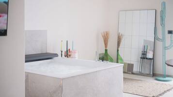Um banheiro moderno com uma banheira grande, um espelho e uma decoração com cactos.