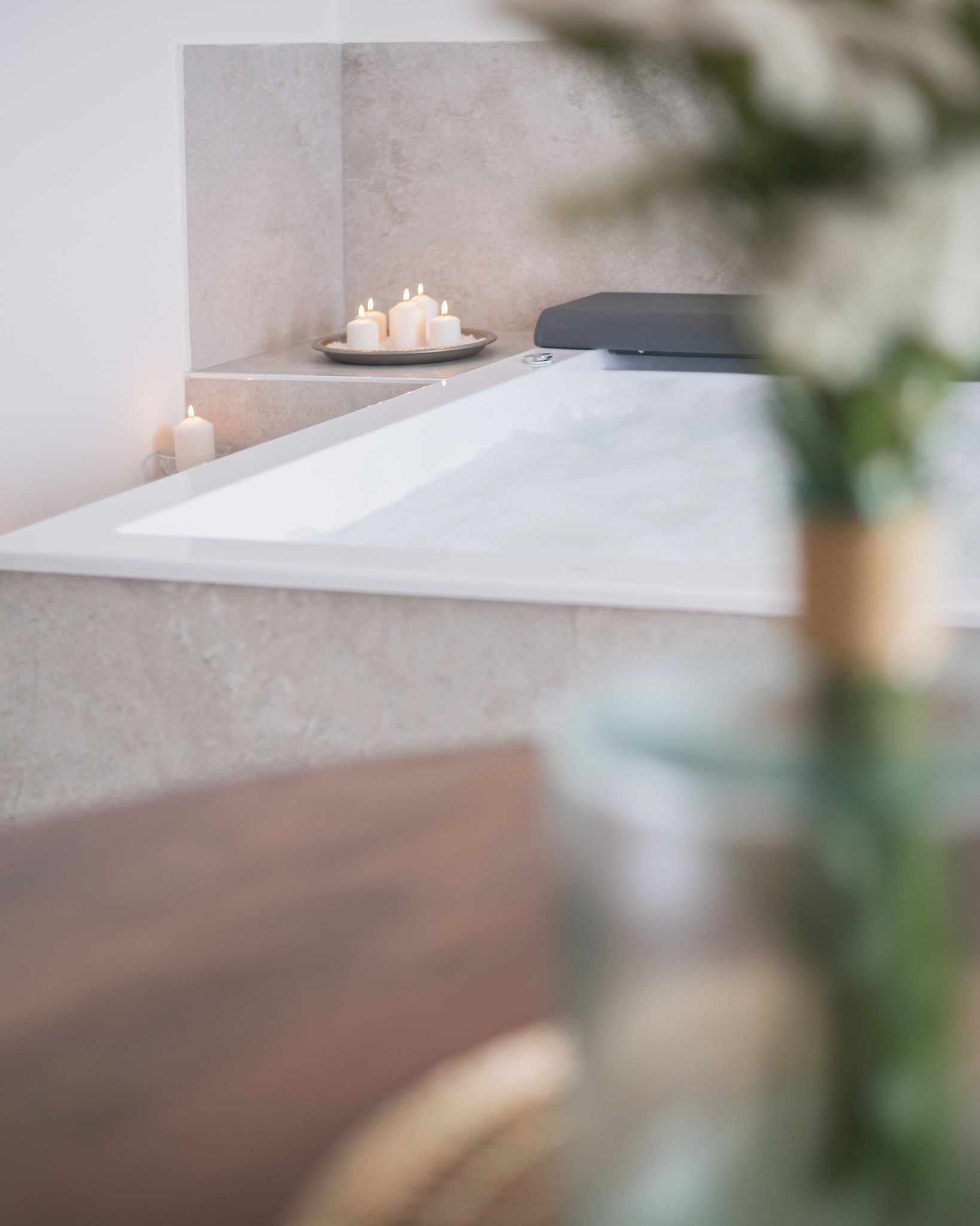 Uma área de spa com banheira, velas e uma pequena mesa.