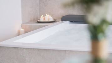 Uma área de spa com banheira, velas e uma pequena mesa.