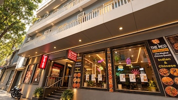 Um hotel com varanda, sinalização para 'The MCO Restaurant' e uma escadaria visível que leva à entrada.