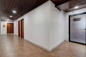 Um corredor com teto de madeira, paredes brancas e chão de azulejos.