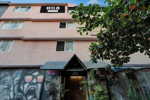 Edifício de hotel com placa que diz 'HOTEL' e um mural na fachada inferior.