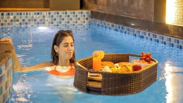 Pessoa em piscina com cesta contendo alimentos.