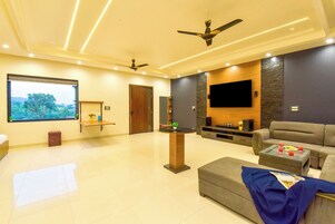 Uma sala de estar moderna com televisão de tela plana, sofá, mesa de centro e ventilador de teto.