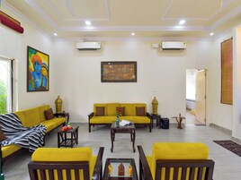 Uma sala de estar com um sofá amarelo, uma mesa de centro e um quadro na parede.