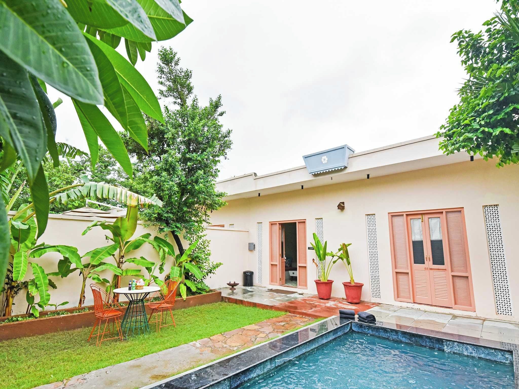 Um imóvel residencial com piscina, varanda coberta e área de jardim com plantas em vasos.
