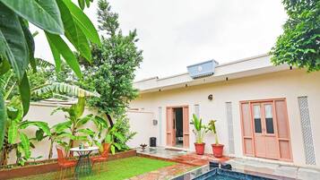Um imóvel residencial com piscina, varanda coberta e área de jardim com plantas em vasos.