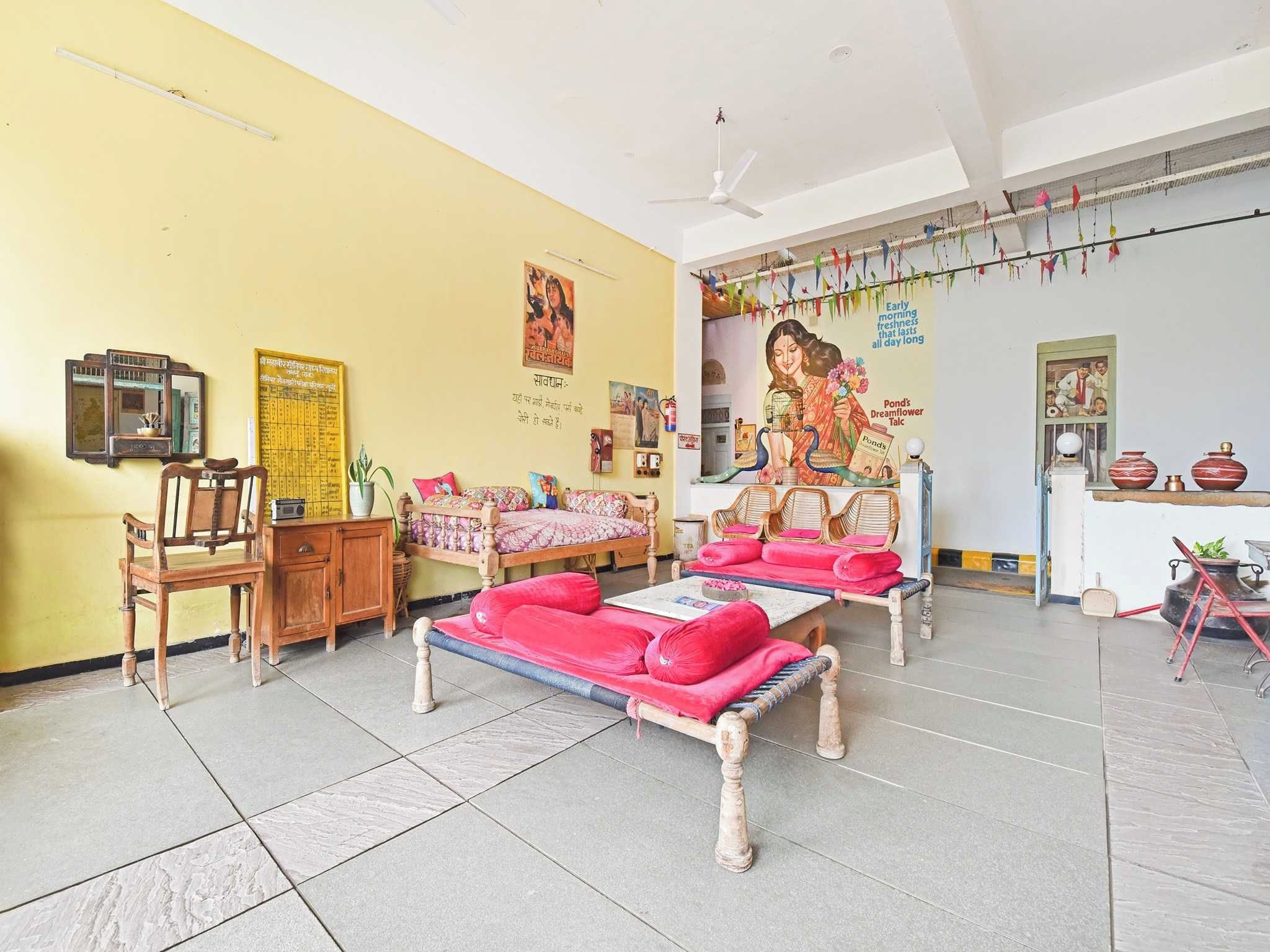 Quarto com duas camas, um armário de madeira, ventilador de teto e parede decorada com cartazes e enfeites.