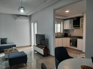 Uma sala de estar moderna com sofá, banqueta e TV de tela plana.