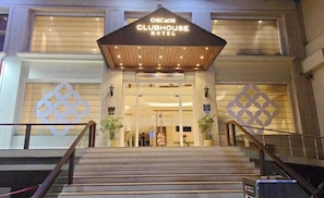 Exterior do Chekin Clubhouse Hotel, com entrada destacada, escadaria que leva à entrada e padrões geométricos decorativos na fachada.