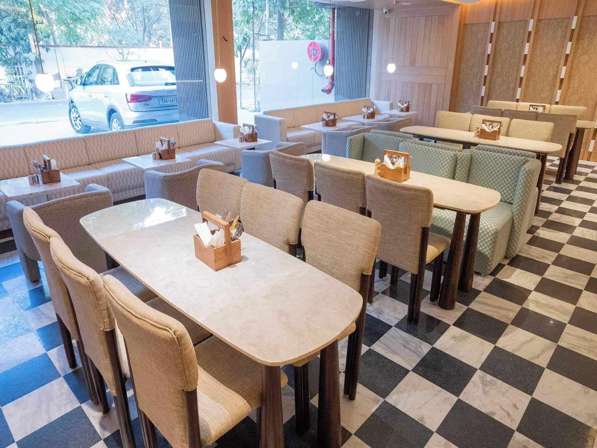Um restaurante com piso xadrez, cabines e mesas.