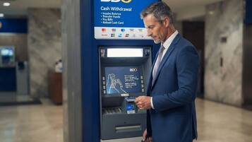 Um homem usando um caixa eletrônico BDO no saguão de um hotel.