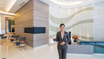 Um lobby moderno com balcão de recepção, área de estar e parede curva com linhas verticais.