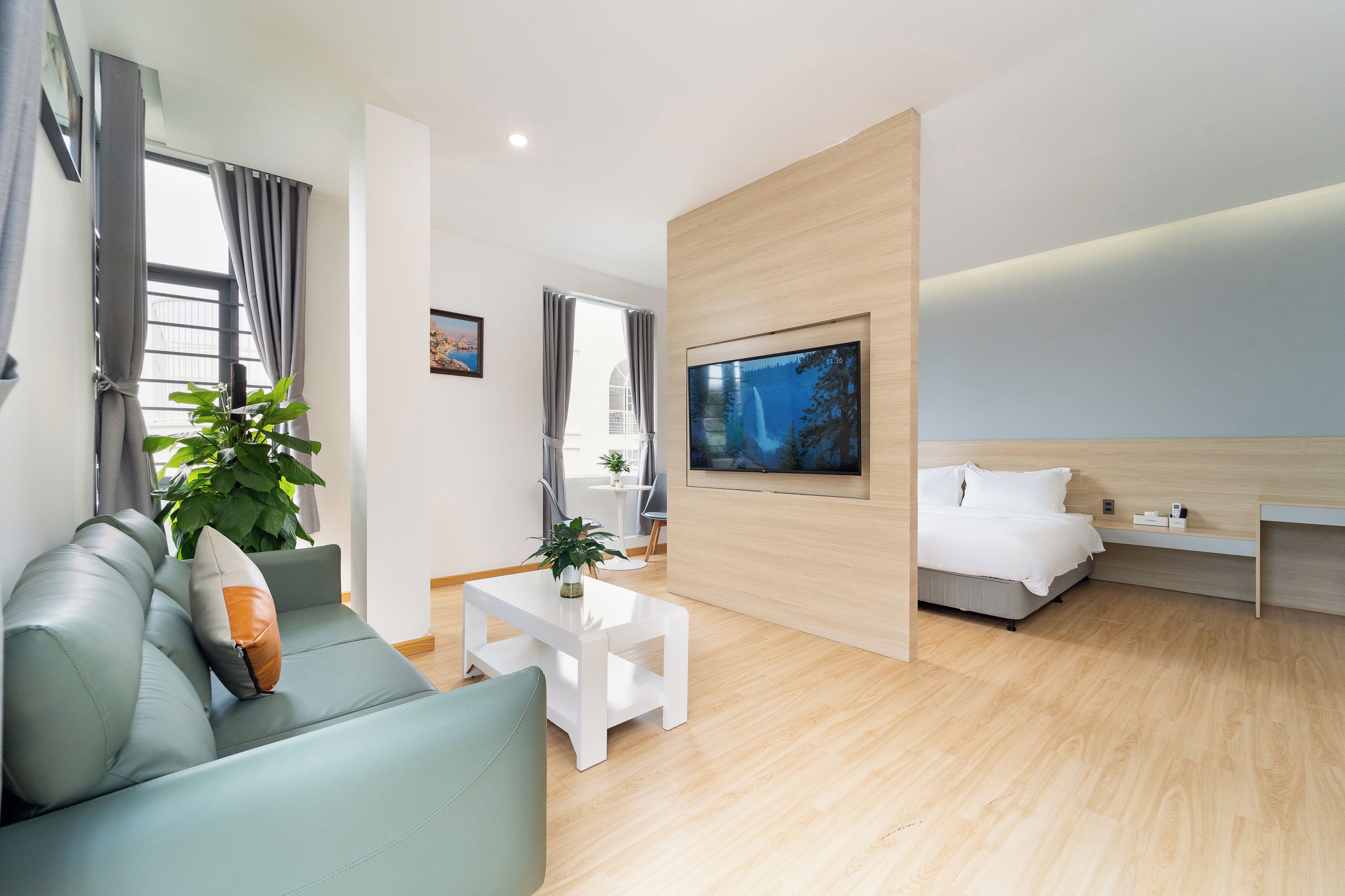 Quarto de hotel moderno com sofá, mesa de centro, televisão e cama.