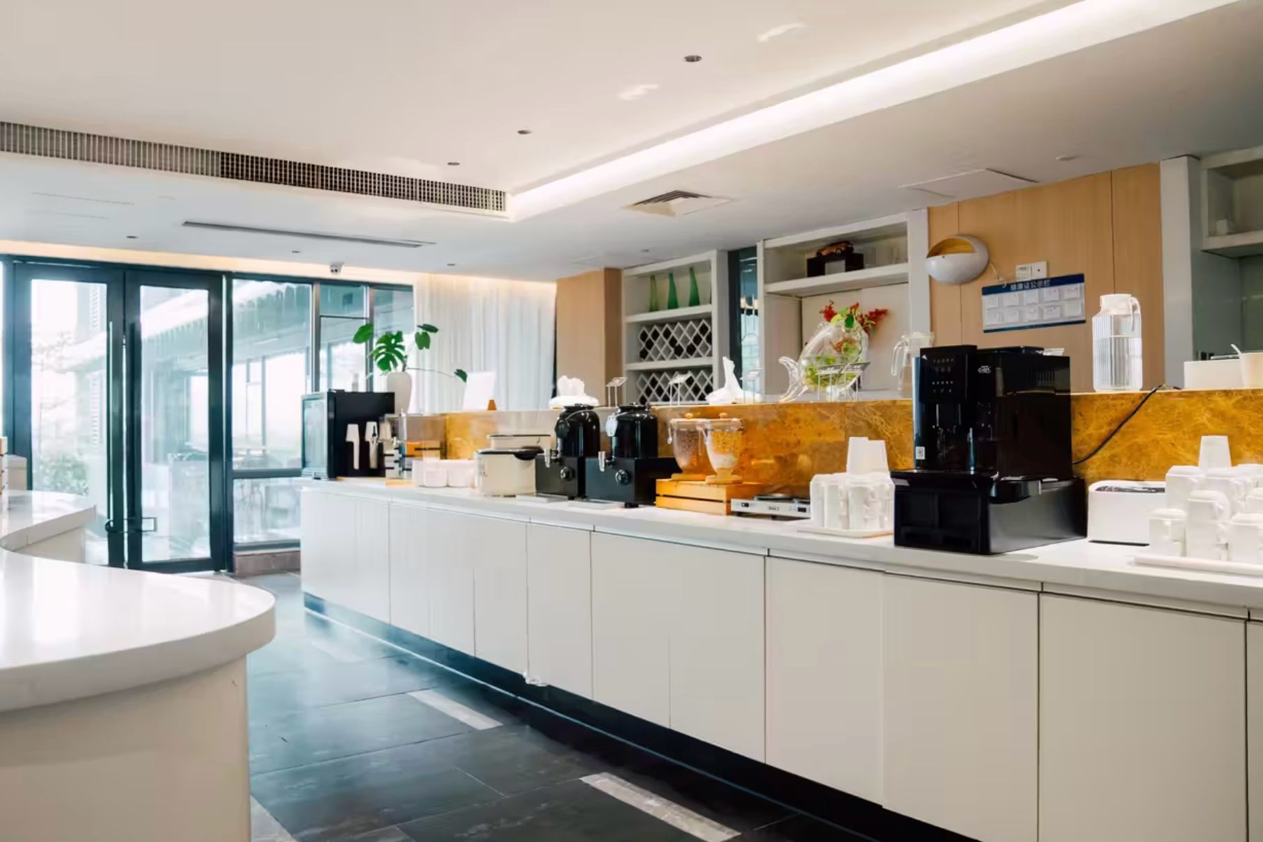 Um hall de hotel moderno com uma mesa de recepção, máquinas de café e um bebedouro.