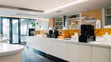 Um hall de hotel moderno com uma mesa de recepção, máquinas de café e um bebedouro.
