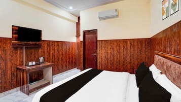 Quarto de hotel com cama, escrivaninha, televisão e ar condicionado.