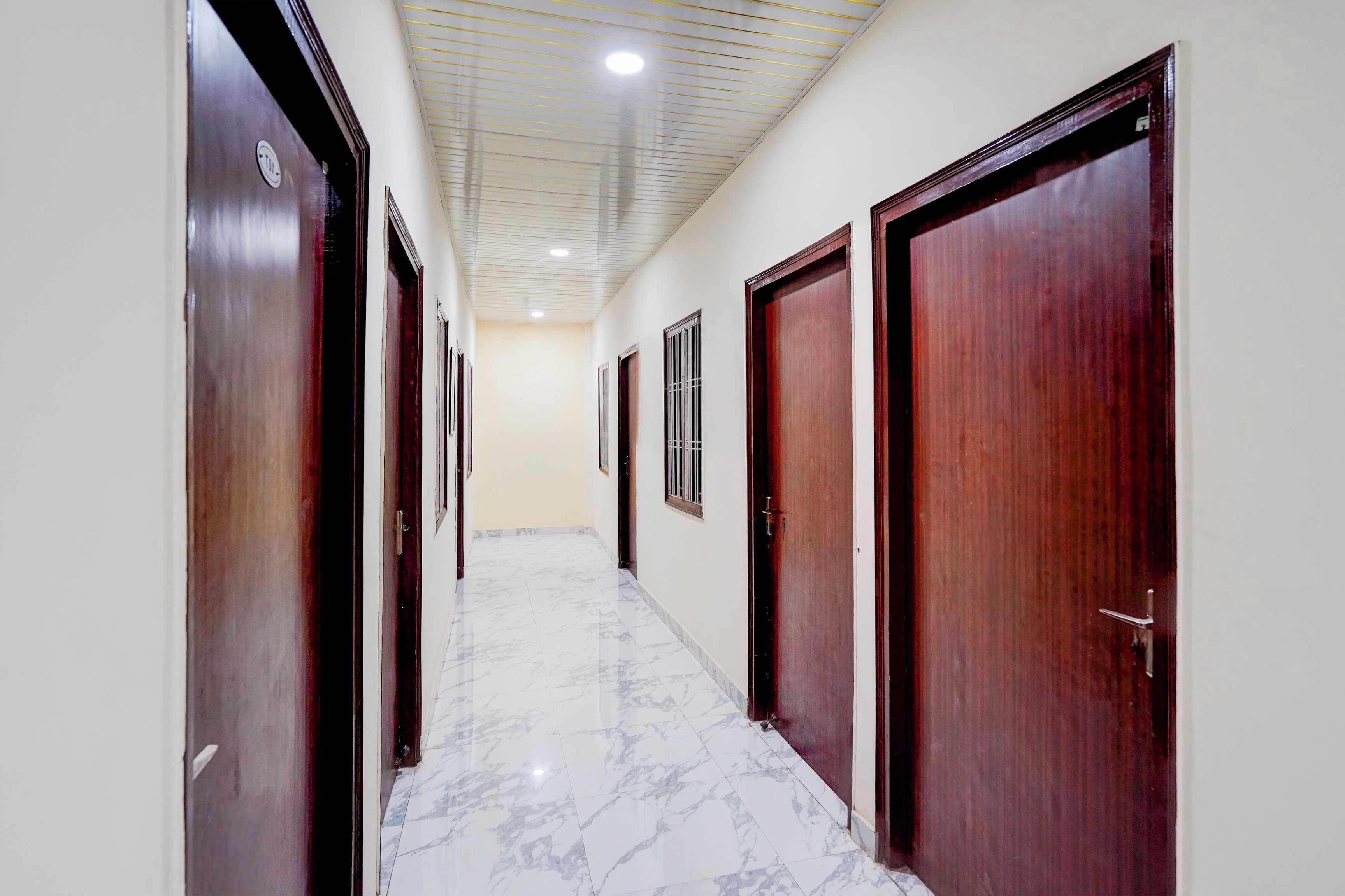 Corredor com portas de madeira, paredes brancas e chão em azulejos.