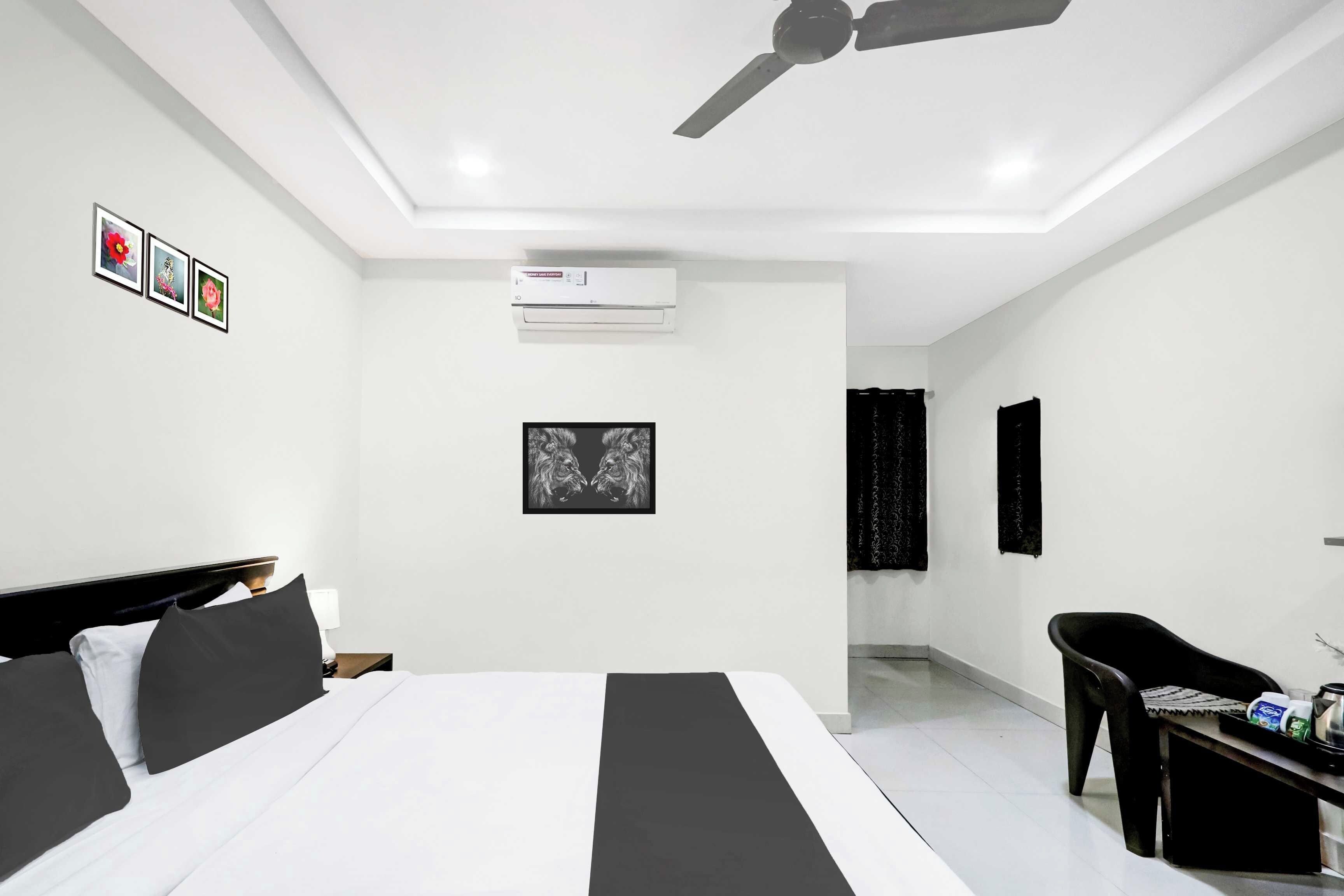 Quarto de hotel moderno com cama, escrivaninha, cadeira, ar condicionado e ventoinha no teto.