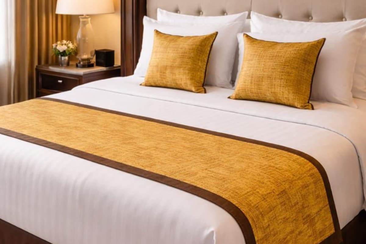 Quarto de hotel com uma cama grande, cabeceira, mesa de cabeceira com abajur e piso coberto por carpete.