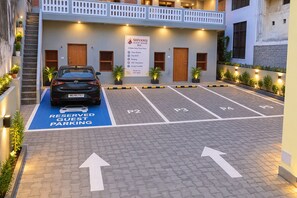 Hotel com área de estacionamento reservada para hóspedes, escadas e uma placa com a lista de comodidades.