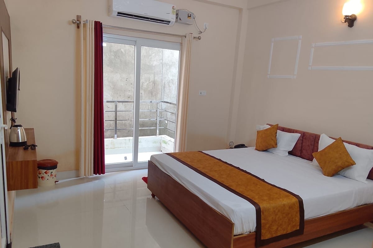 Quarto de hotel com cama grande, porta de vidro deslizante para a varanda, televisão de tela plana e cafeteira.